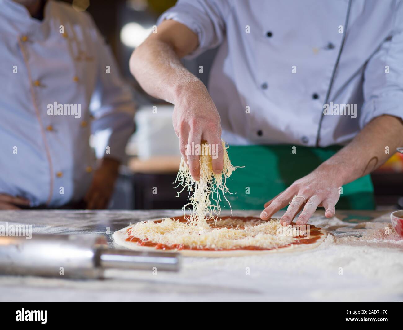 chef sprinkling cheese over fresh pizza dough Stock Photo - Alamy