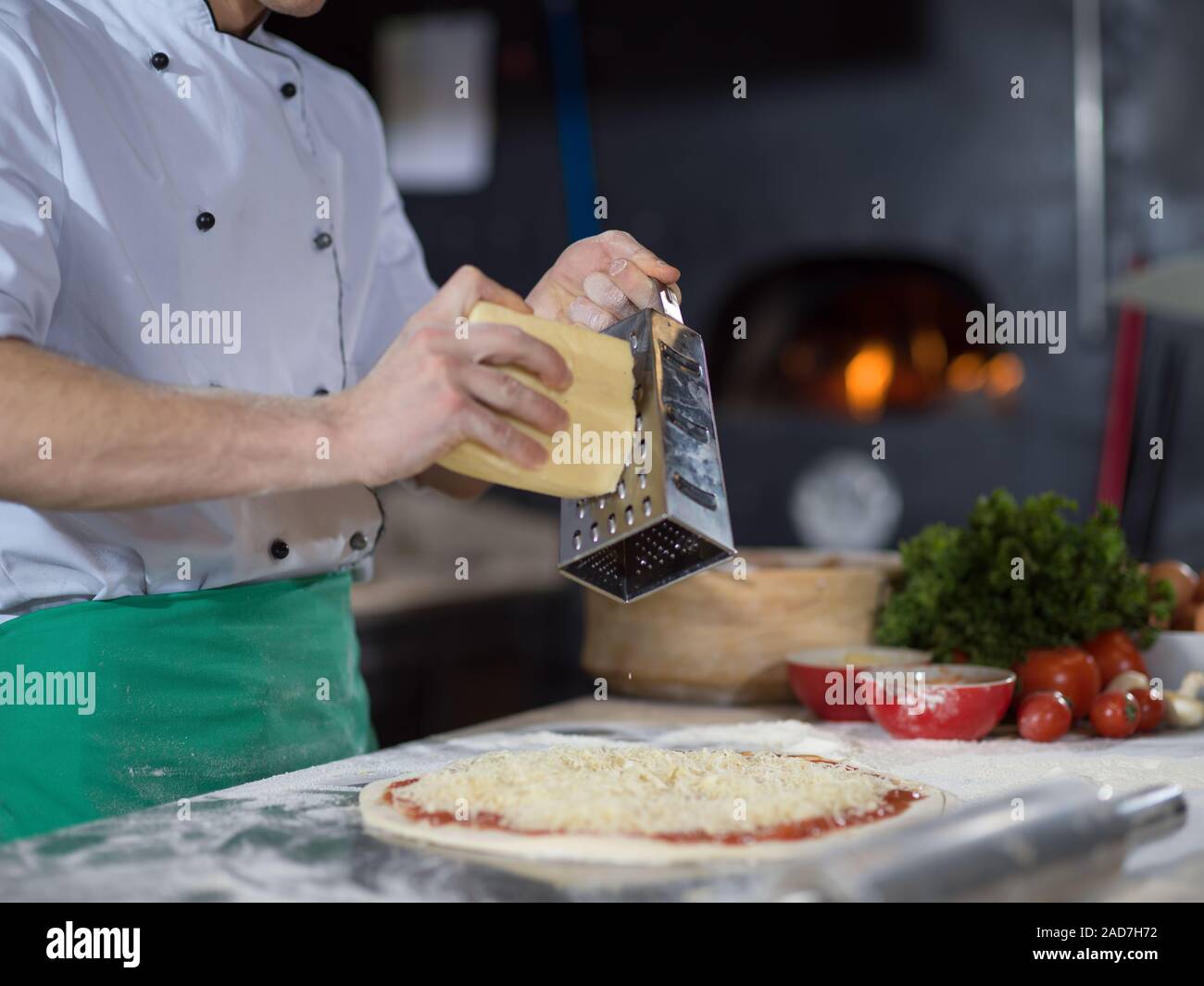 chef sprinkling cheese over fresh pizza dough Stock Photo - Alamy