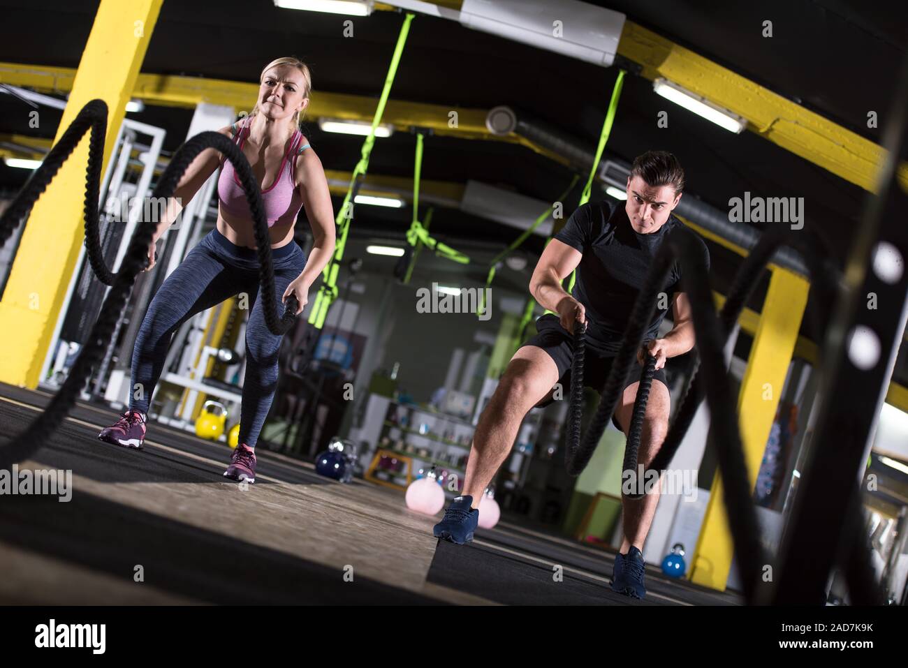 sports couple doing battle ropes cross fitness exercise Stock Photo - Alamy