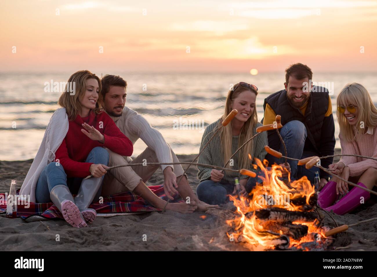 Group Of Young Friends Sitting By The Fire at beach Stock Photo - Alamy