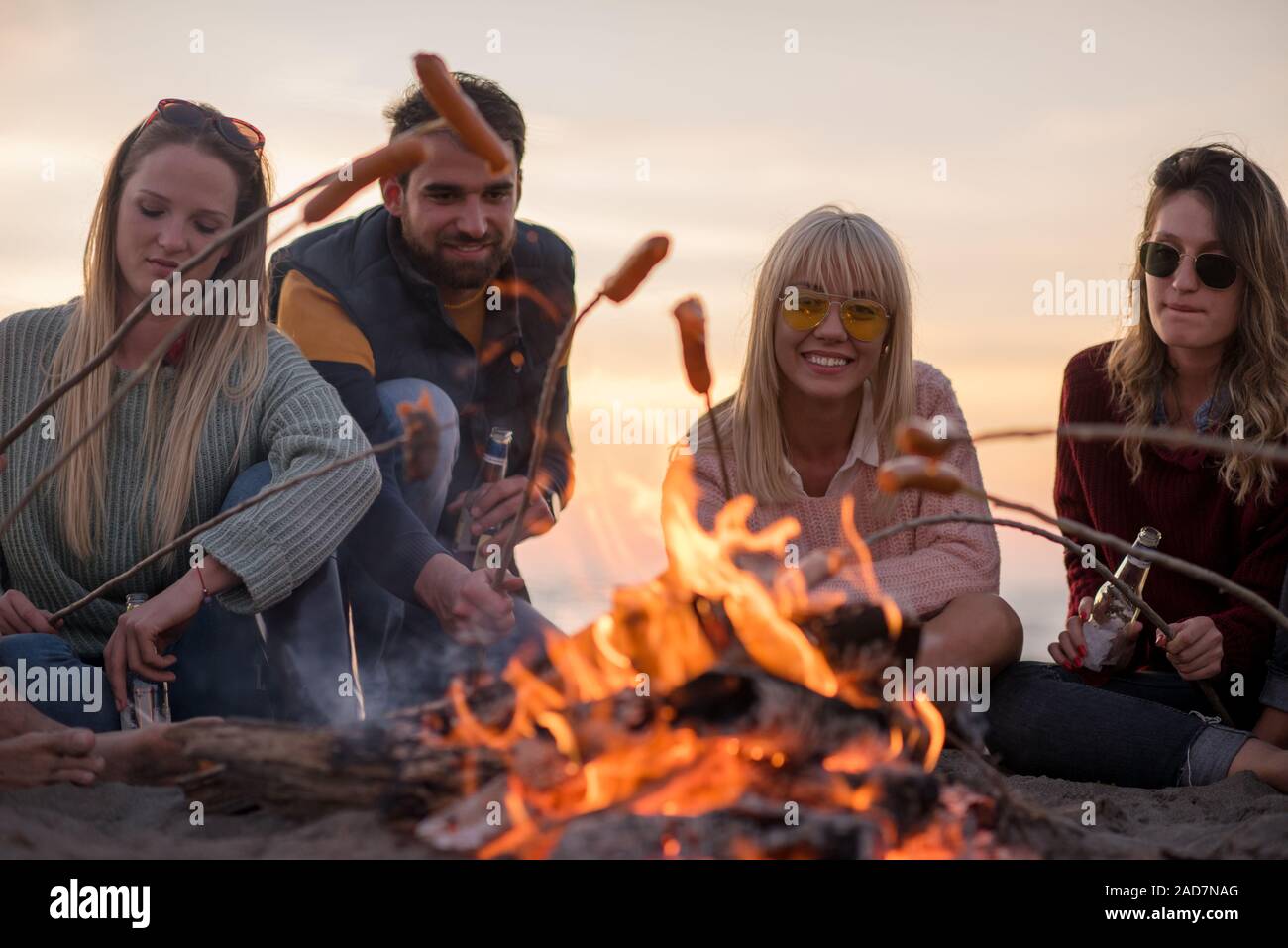 Group Of Young Friends Sitting By The Fire at beach Stock Photo - Alamy