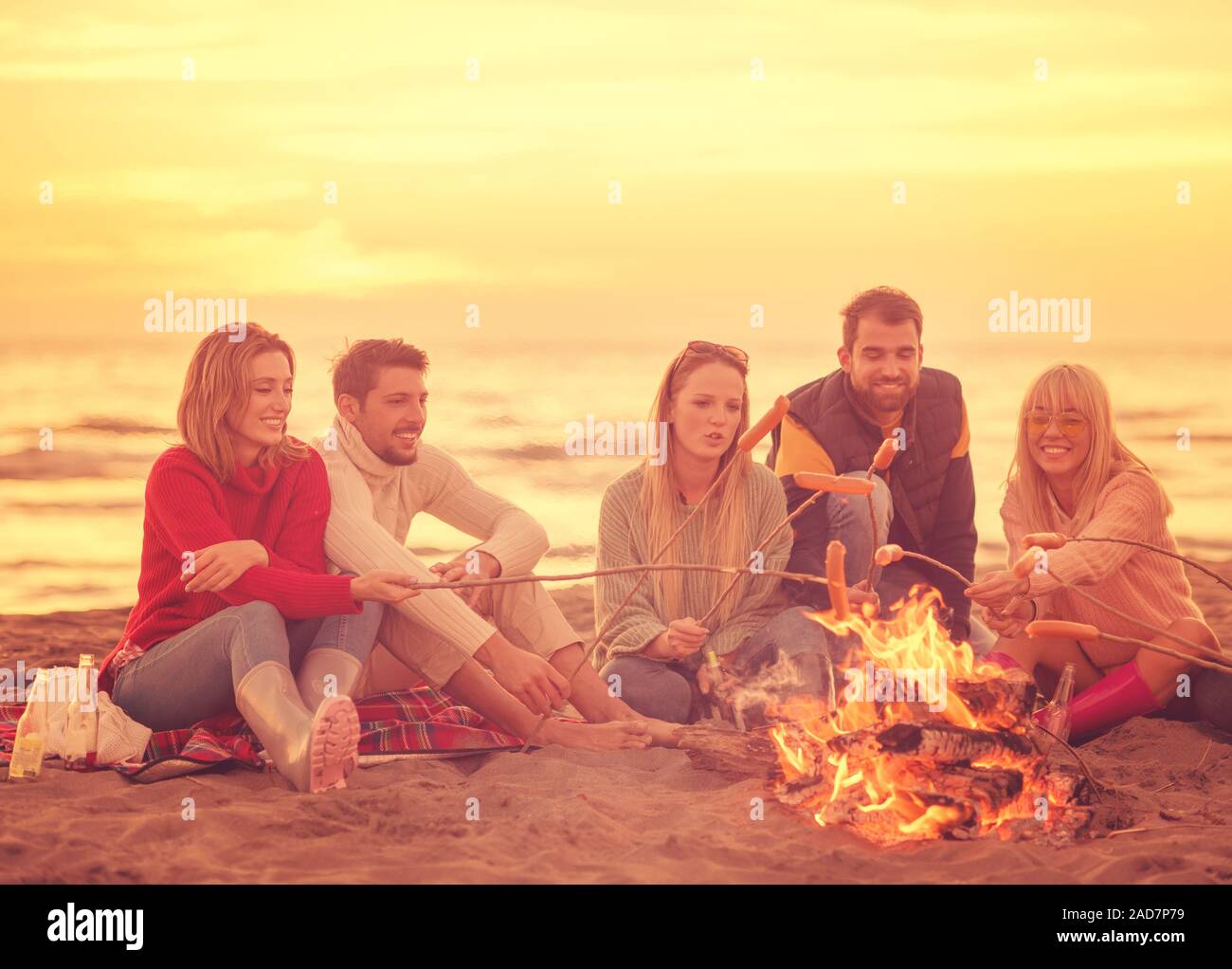Group Of Young Friends Sitting By The Fire at beach Stock Photo - Alamy