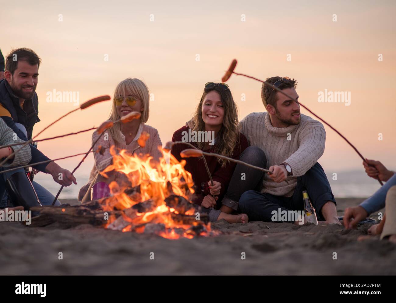 Group Of Young Friends Sitting By The Fire at beach Stock Photo - Alamy