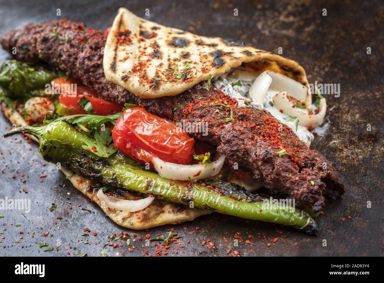 Traditional Adana kebap on a skewer with tomato and yogurt as closeup ...