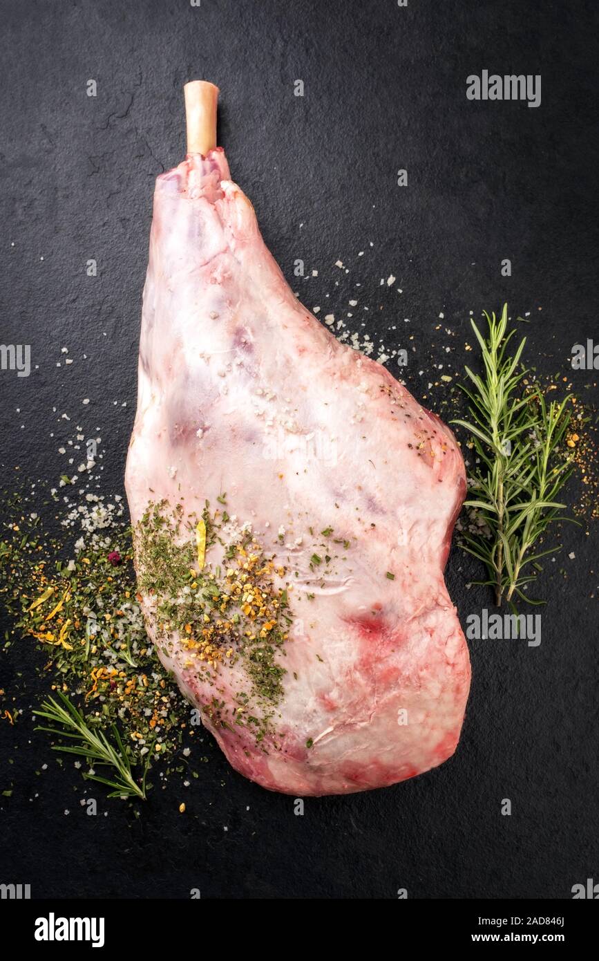 Traditional raw leg of lamb with spice and herb as top view on a slate ...