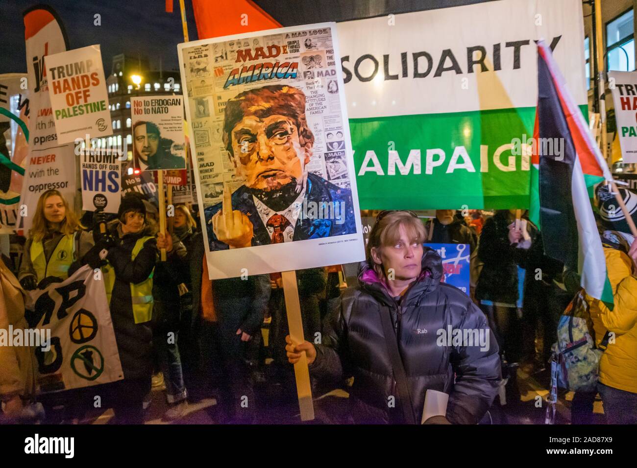London, UK. 3rd December 2019. A woman holds a 'Mad America' placard ...
