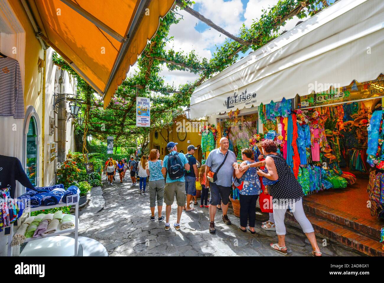 Tourists walk the narrow shaded path past cafes, shops and boutiques at ...