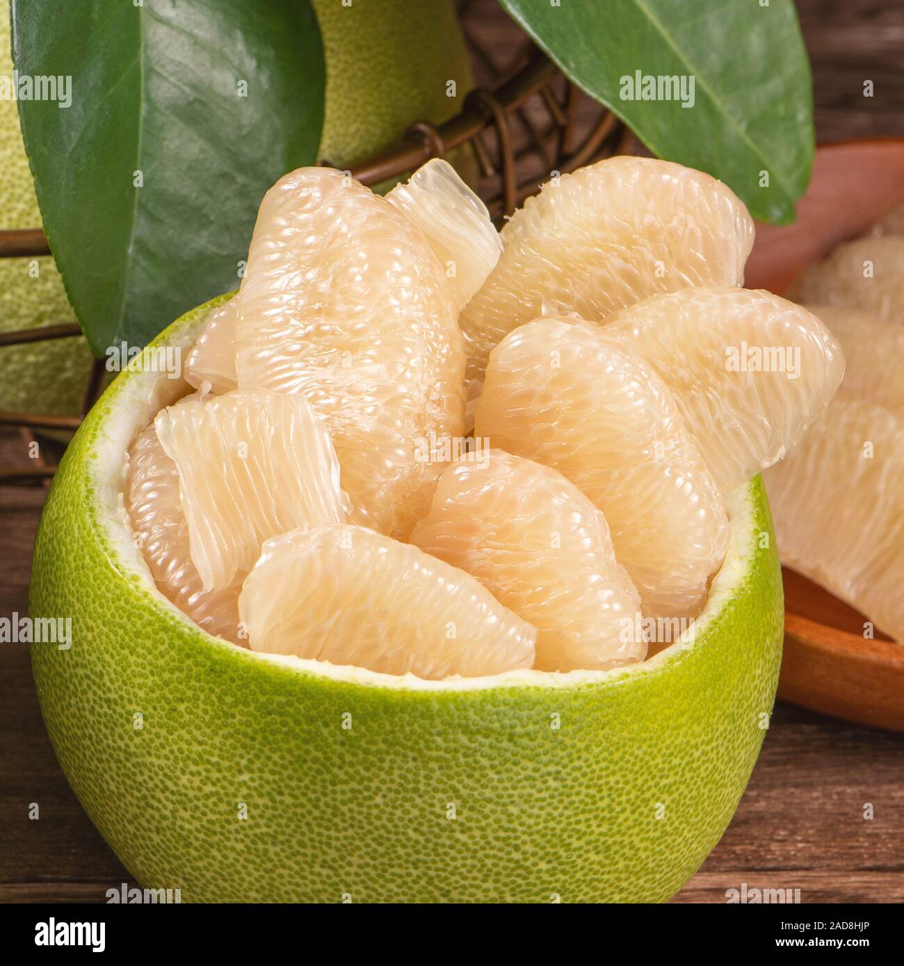 Fresh peeled pomelo, grapefruit, shaddock with green leaves on dark ...