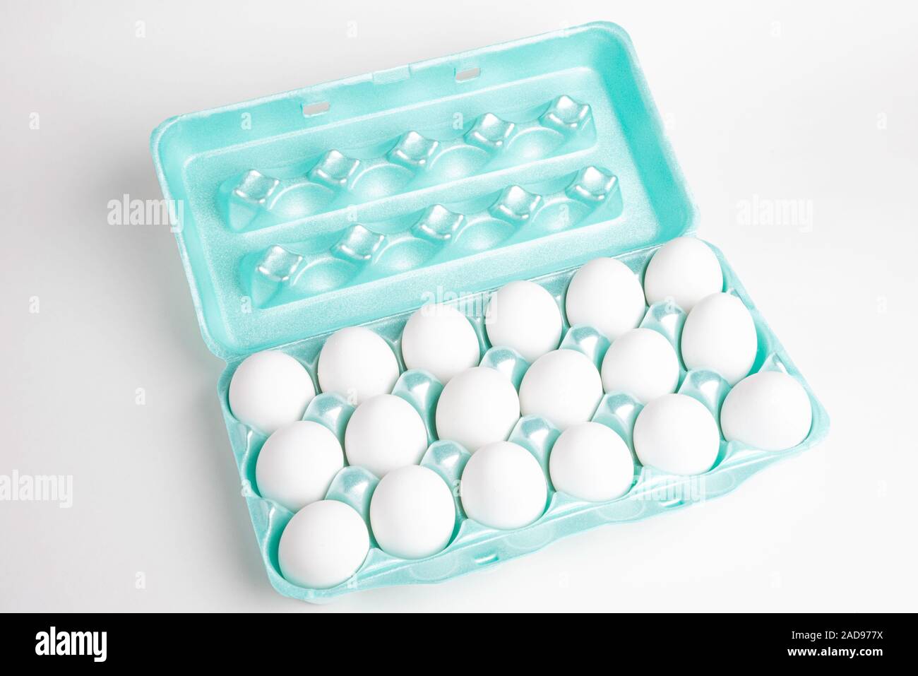 A close-up shot of a bright green styrofoam crate full of white eggs ...