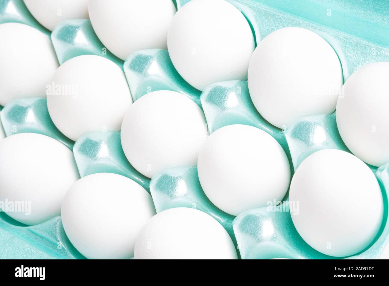 A close-up shot of a bright green styrofoam crate full of white eggs ...