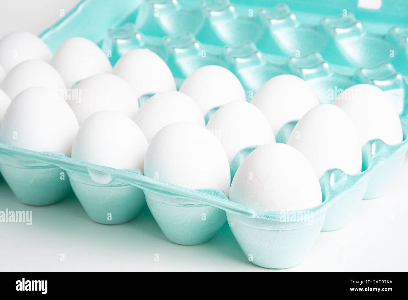 A close-up shot of a bright green styrofoam crate full of white eggs ...