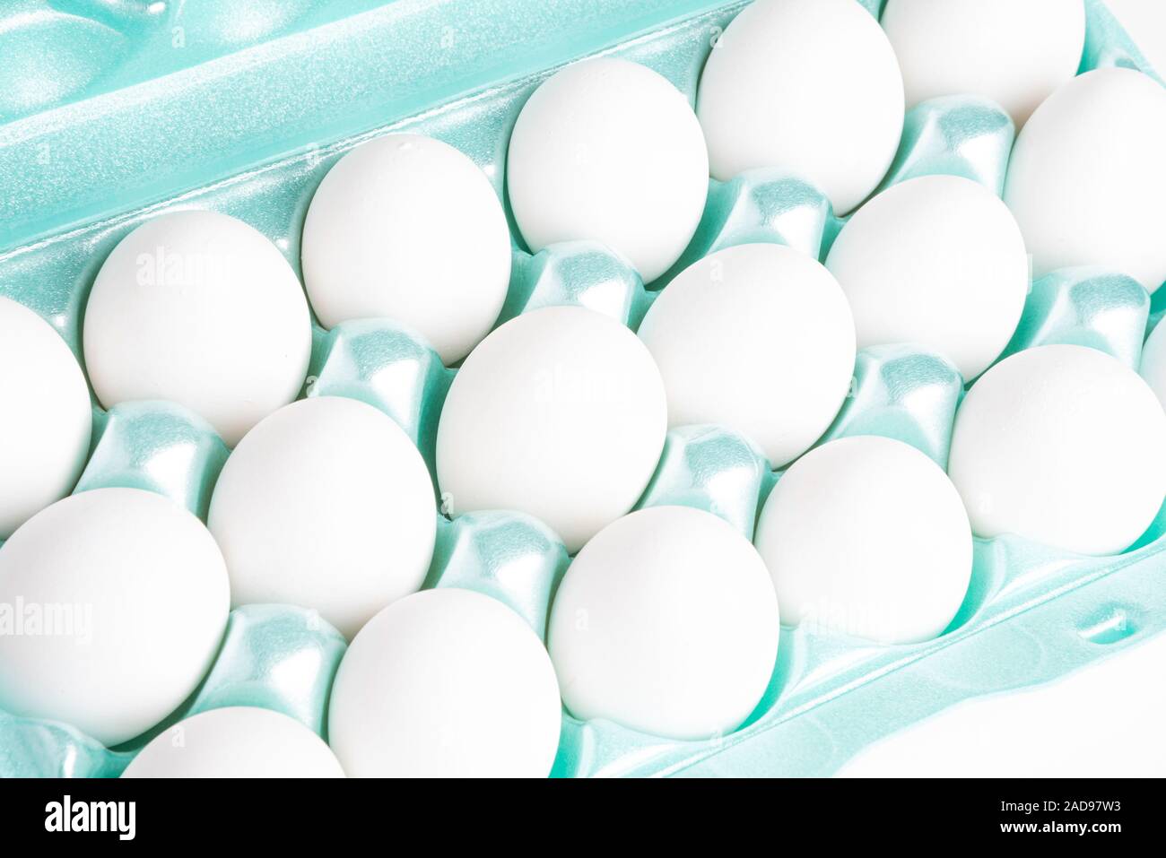 A close-up shot of a bright green styrofoam crate full of white eggs ...