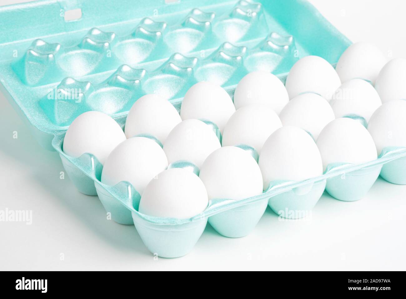 A close-up shot of a bright green styrofoam crate full of white eggs ...