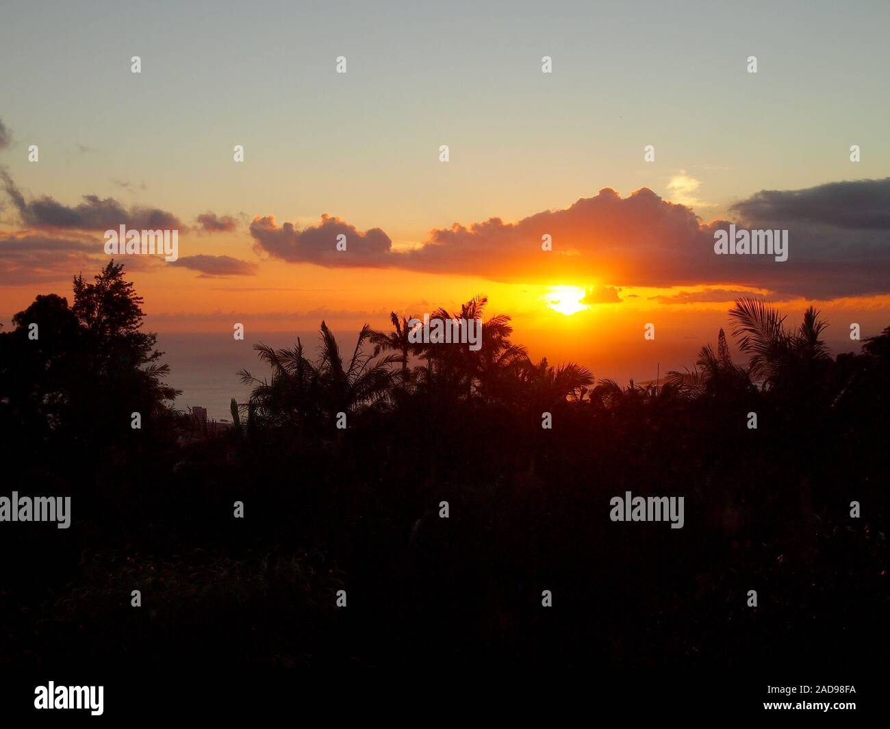 Sunset through the clouds over the ocean seen from Tantalus mountain ...