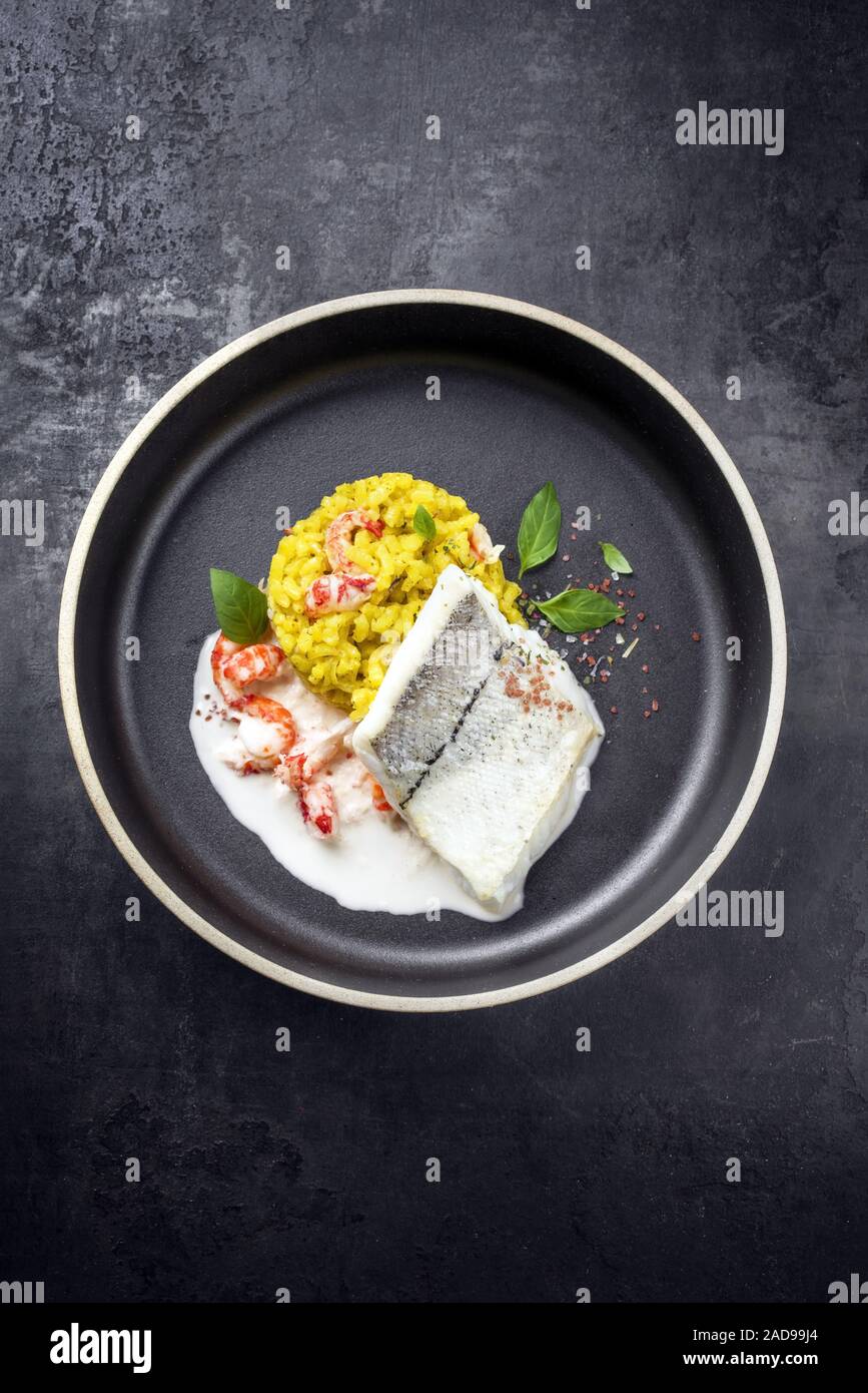 Fried haddock filet with saffron rice and shell prawns in crab sauce as ...