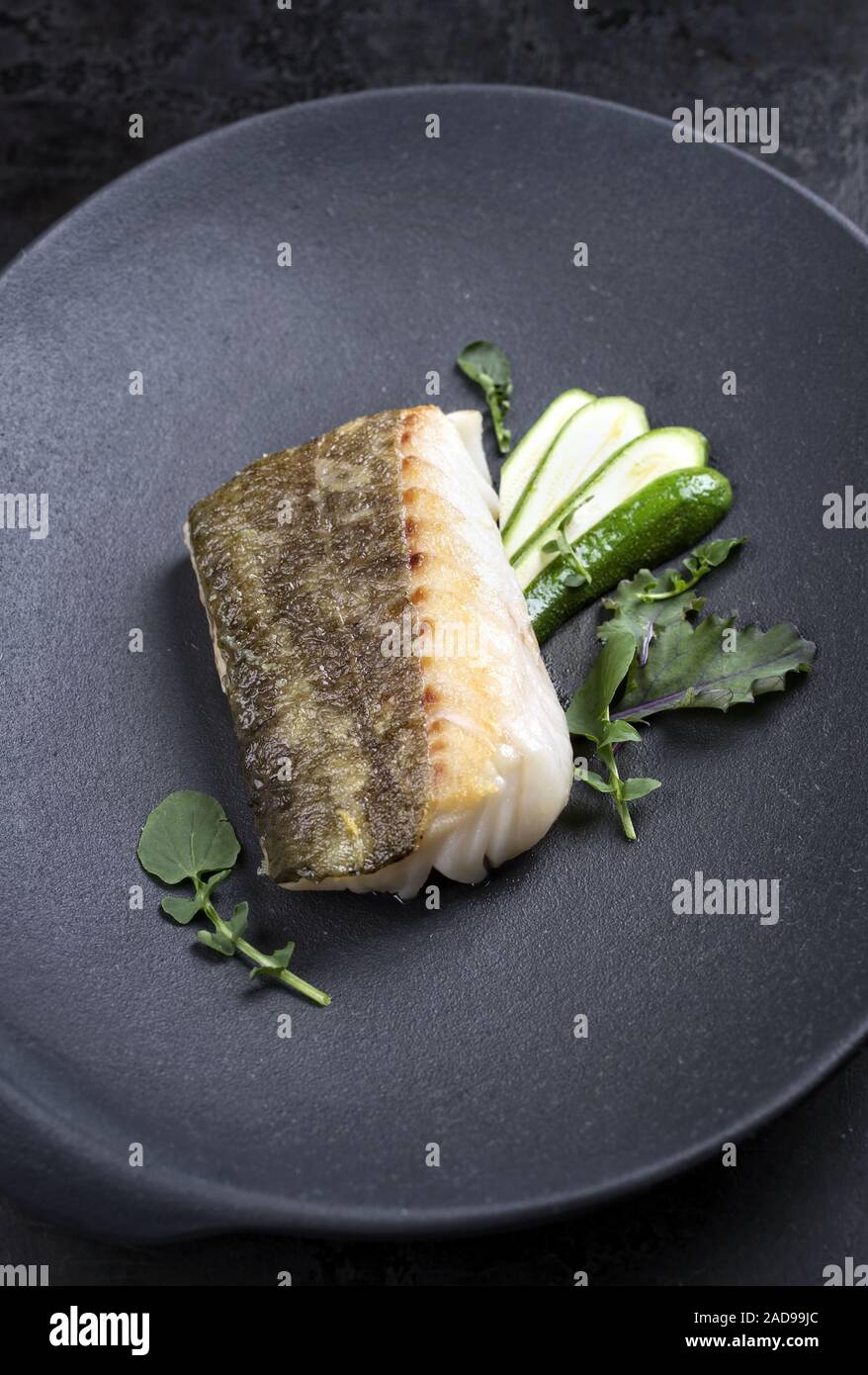 Fried Danish skrei cod fish filet with baby zucchini and lettuce as top ...