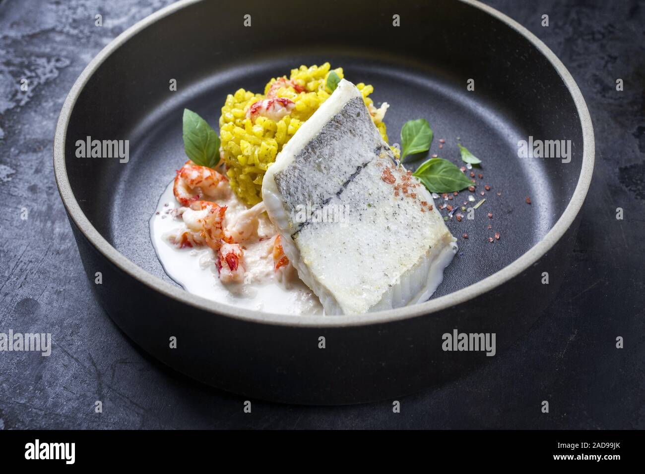 Fried haddock filet with saffron rice and shell prawns in crab sauce as ...