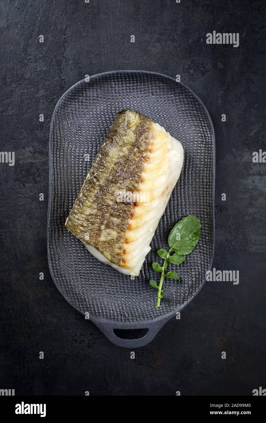 Fried Japanese skrei cod fish filet with wasabi lettuce as top view on ...