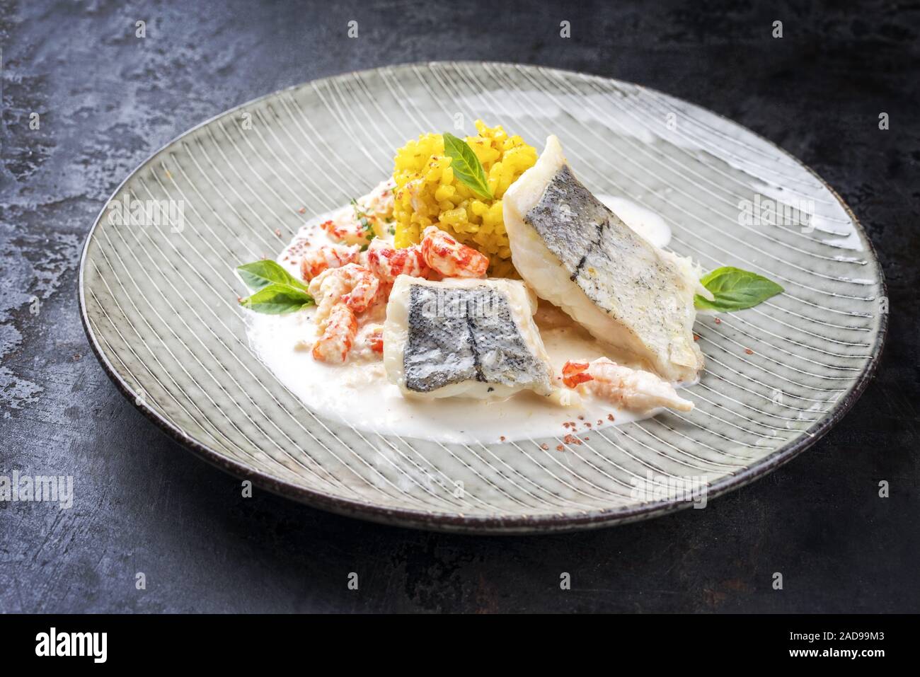 Fried haddock filet with saffron rice and shell prawns in crab sauce as ...