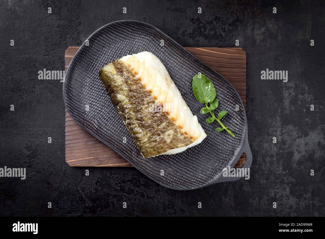 Fried Japanese skrei cod fish filet with wasabi lettuce as top view on ...