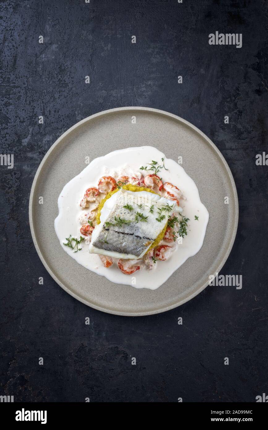 Fried haddock filet with saffron rice and shell prawns in crab sauce as ...