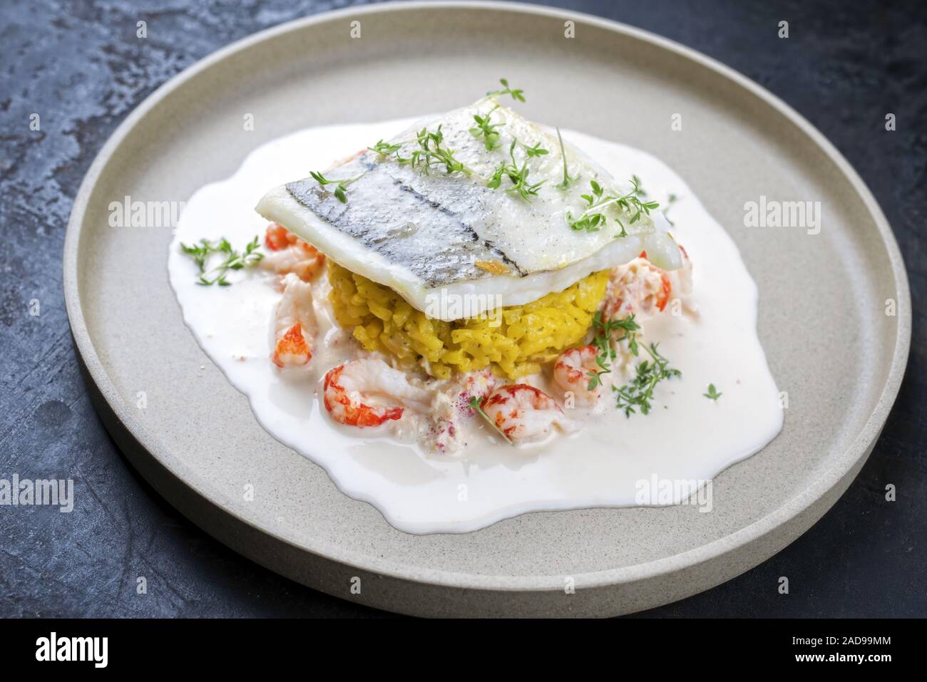 Fried haddock filet with saffron rice and shell prawns in crab sauce as ...