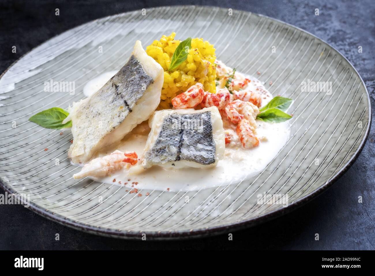 Fried haddock filet with saffron rice and shell prawns in crab sauce as ...