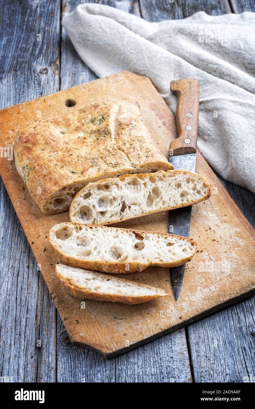 Traditional Italian ciabatta bread with herbs as closeup on a cutting ...