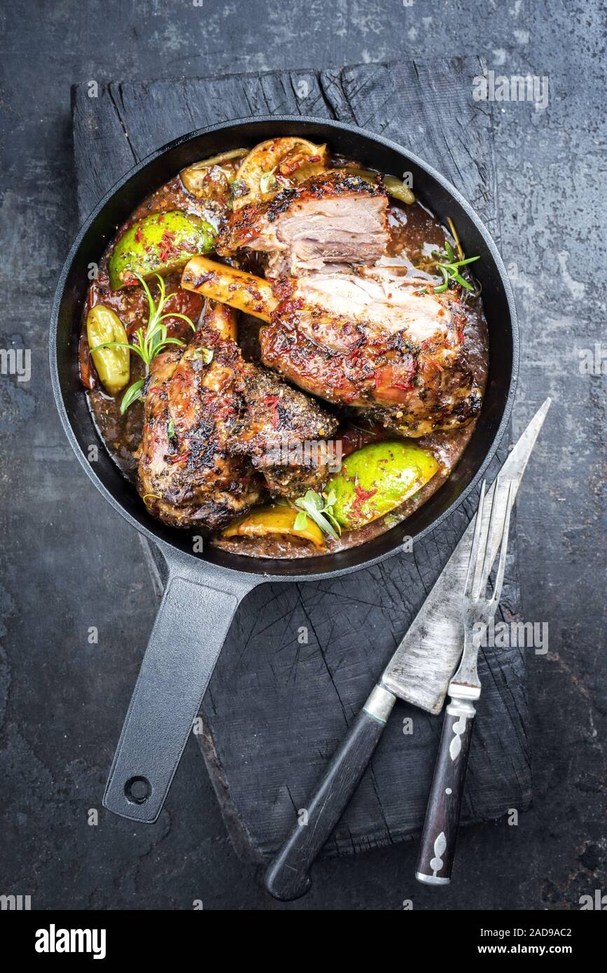 Traditional barbecue leg of lamb with lemon and tomatoes as top view in ...
