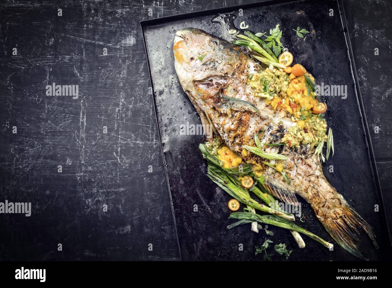 Traditional BBQ parrotfish with mango salsa as top view on a black ...