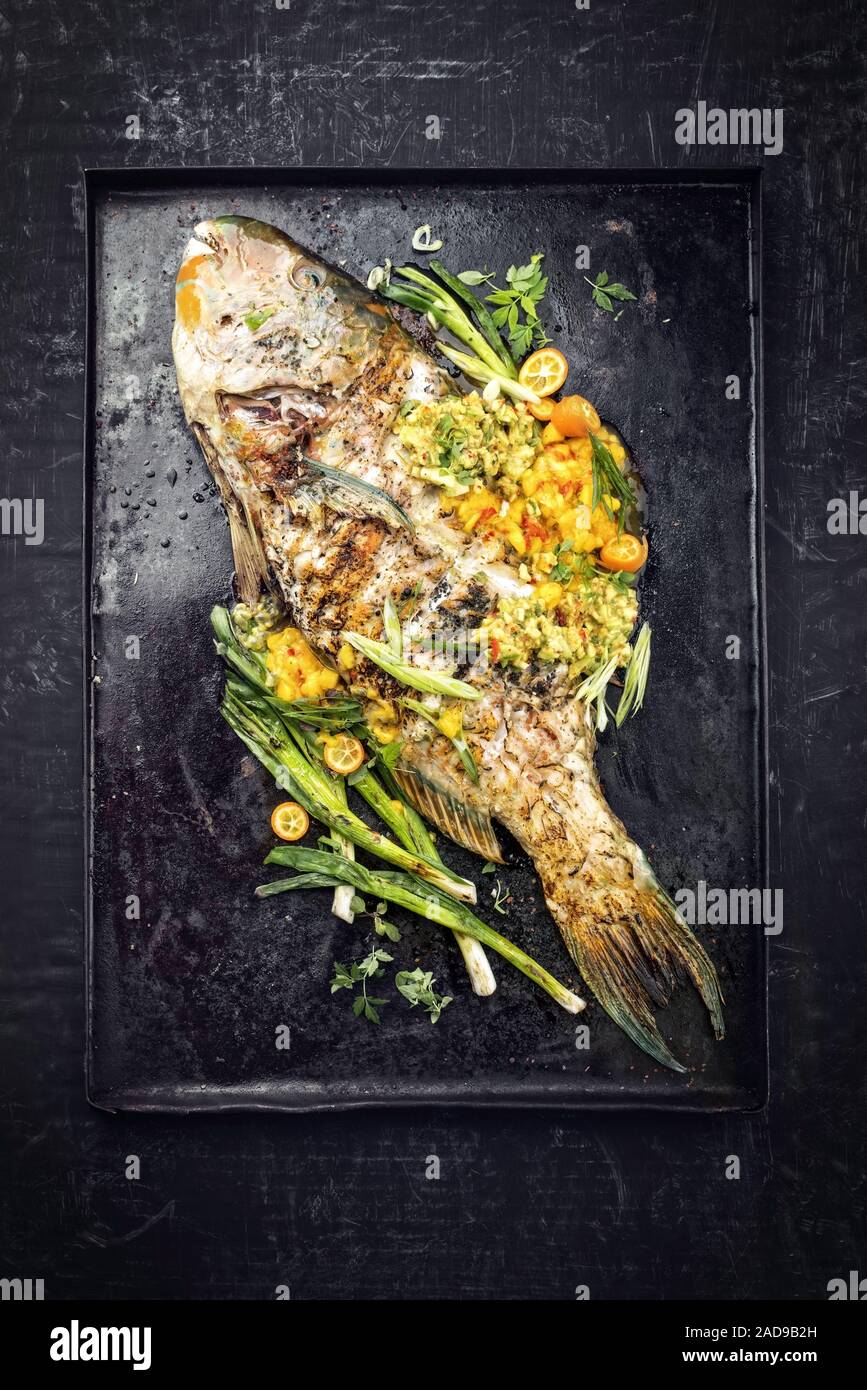 Traditional BBQ parrotfish with mango salsa as top view on a black ...