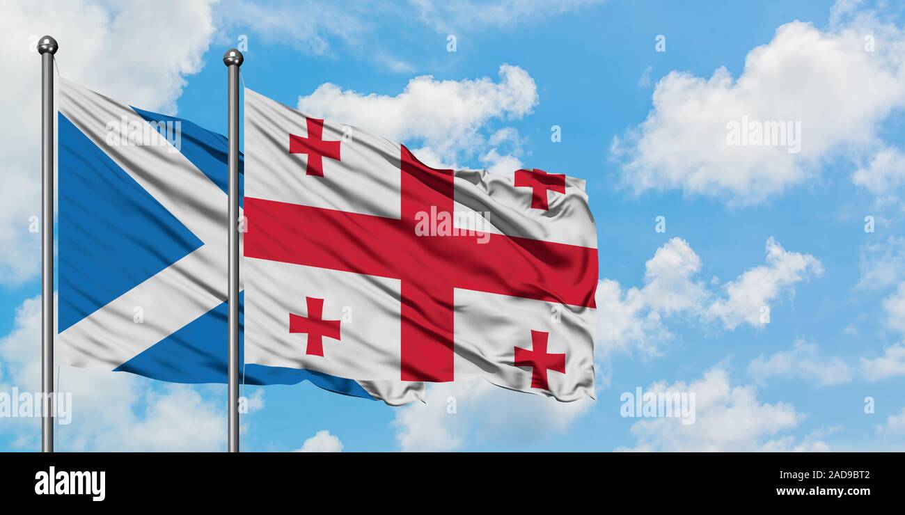 Scotland and Georgia flag waving in the wind against white cloudy blue ...