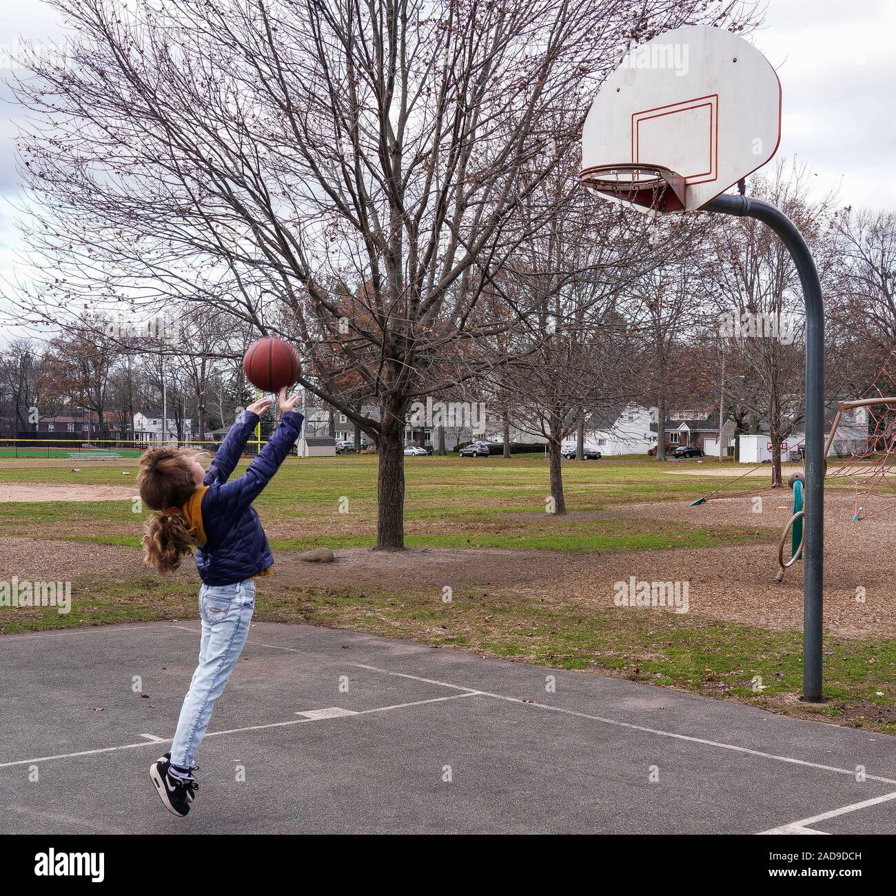 Girl shooting basketball in a school yard Stock Photo - Alamy