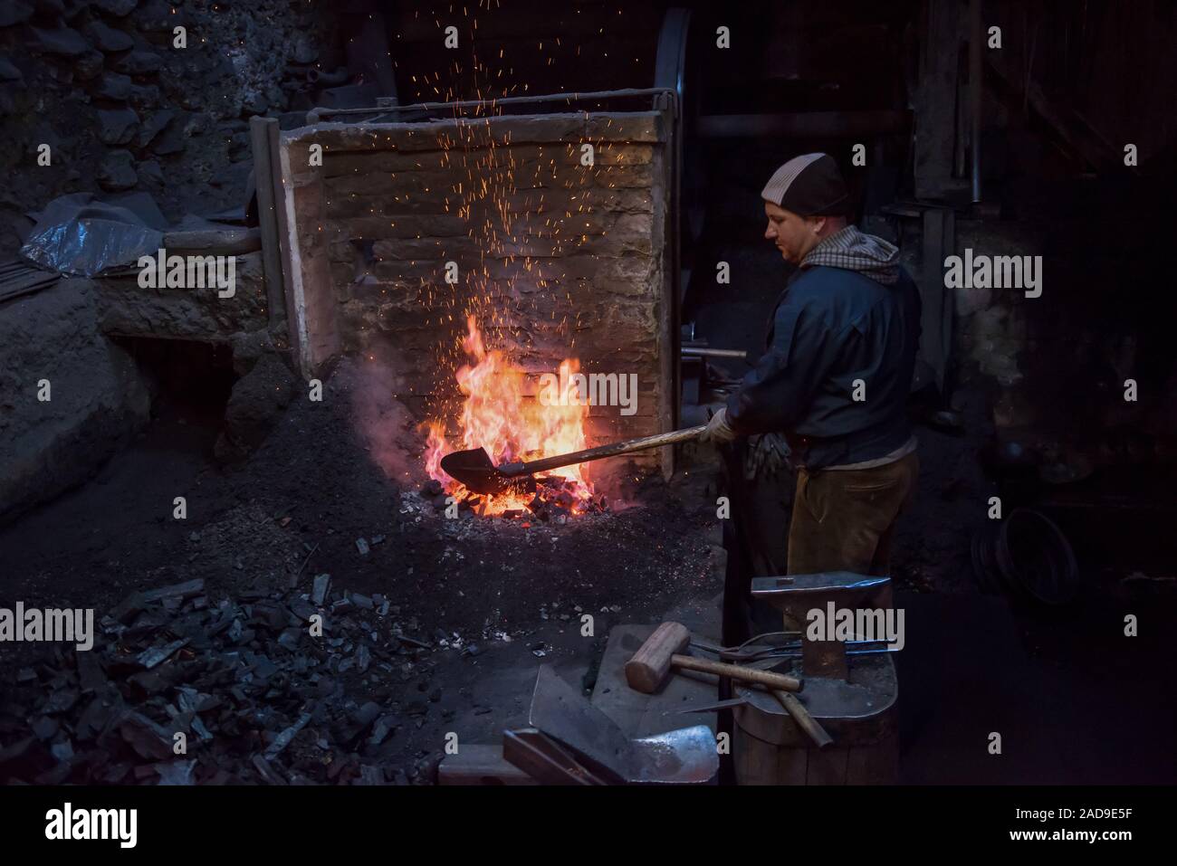 young traditional Blacksmith working with open fire Stock Photo - Alamy