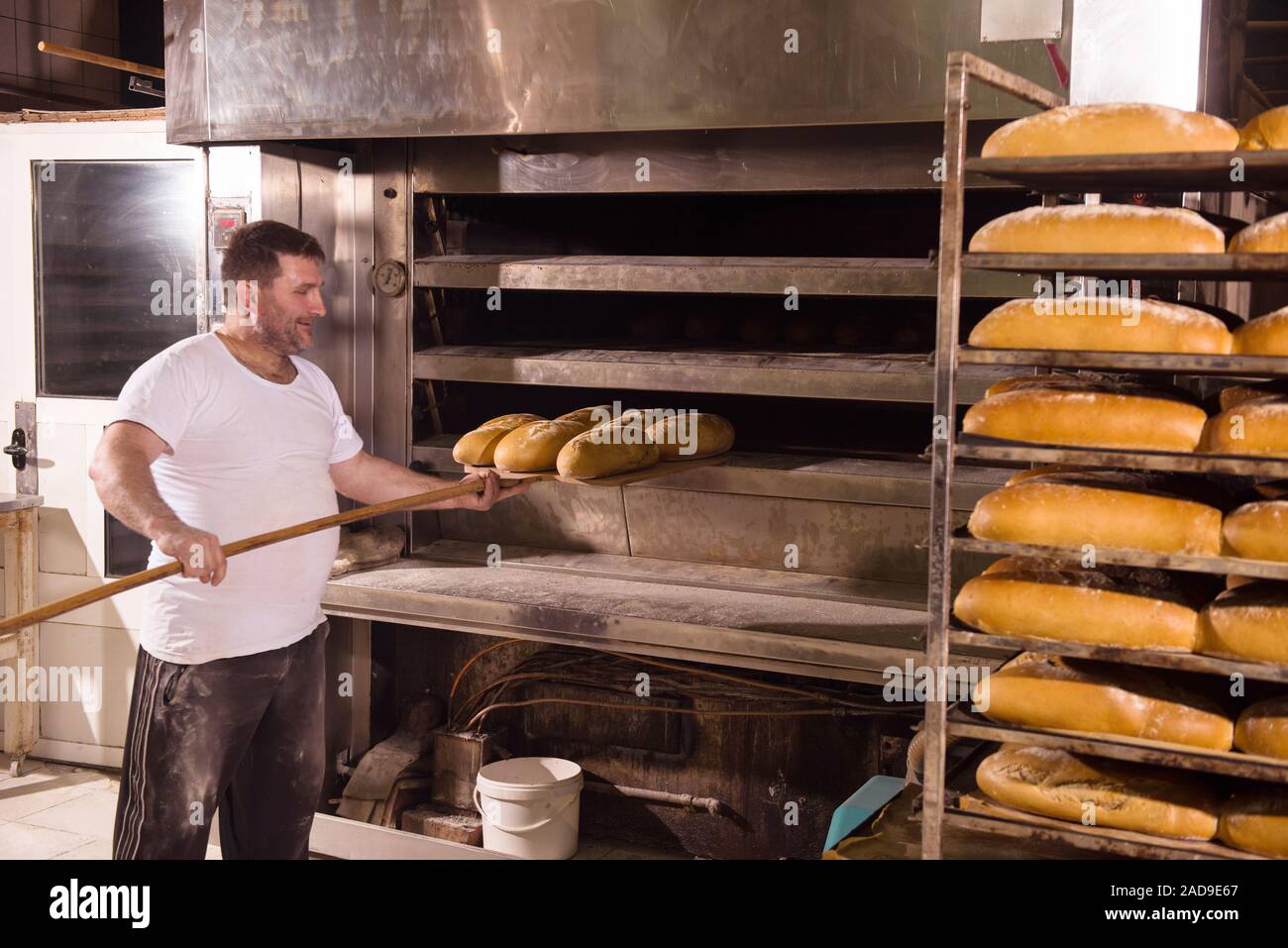 bakery worker taking out freshly baked breads Stock Photo - Alamy