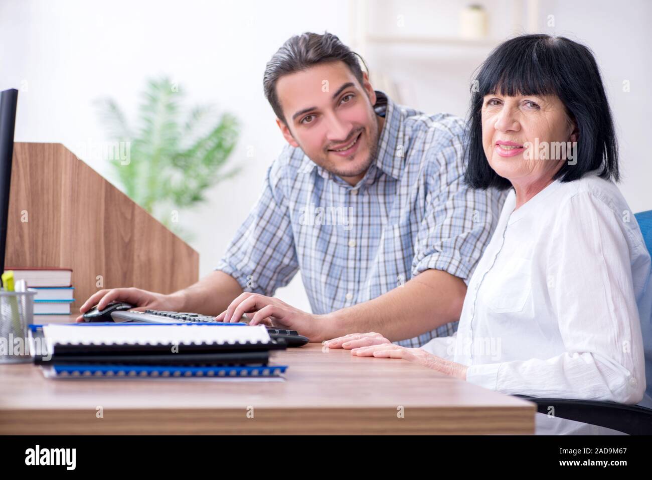 Young male employee explaining to old female colleague how to us Stock ...