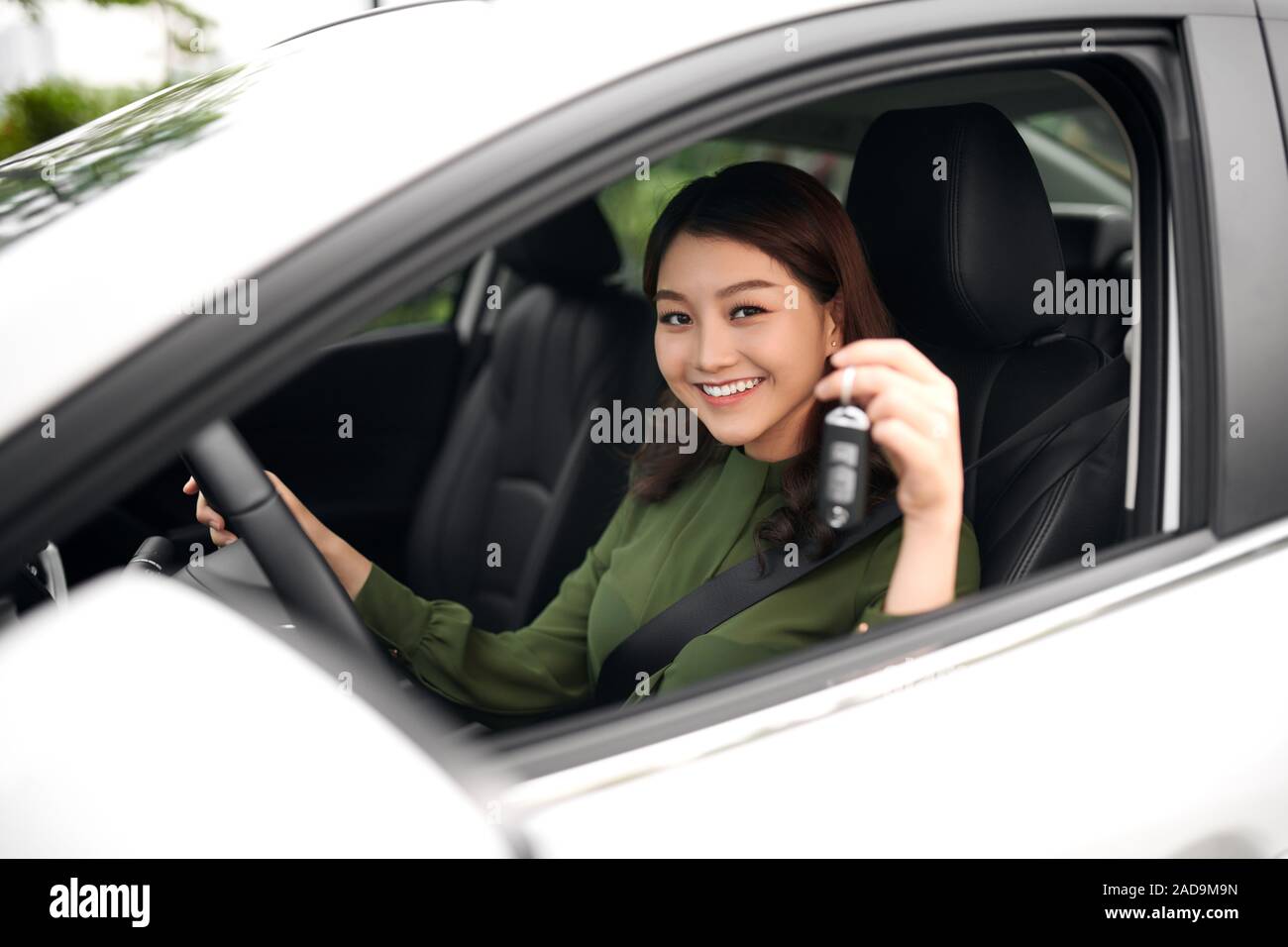 Beautiful young girl driver with car key in hand, happy owner of a new ...