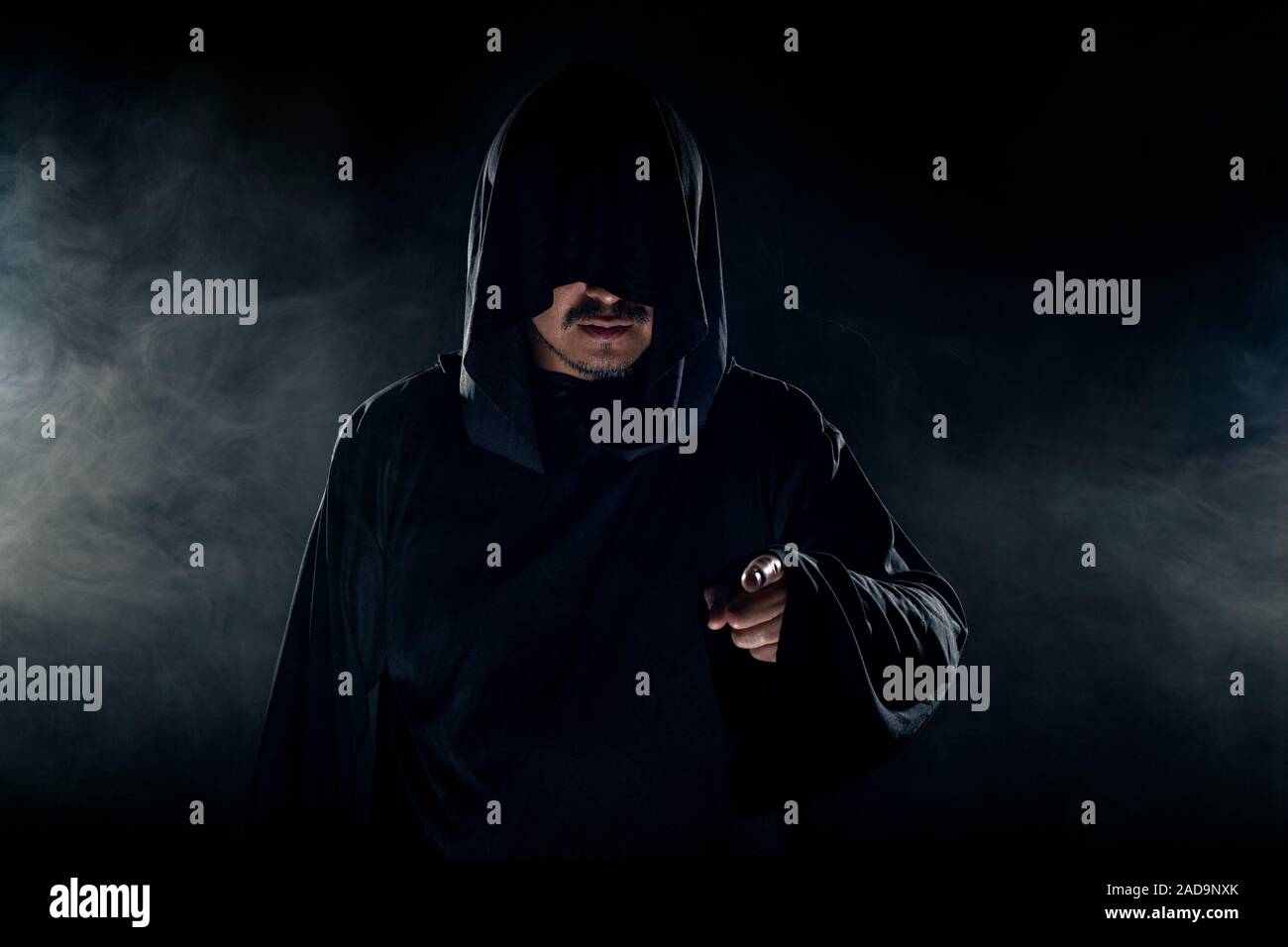 Man dressed in a dark robe looking like a cult leader on a smoky or ...