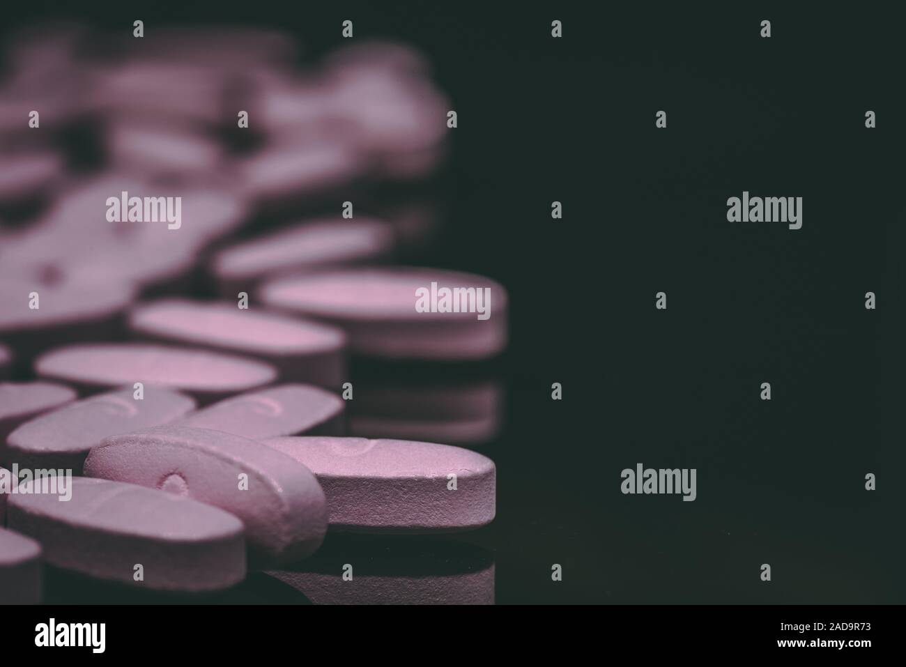Multiple pink pills on black background Stock Photo - Alamy