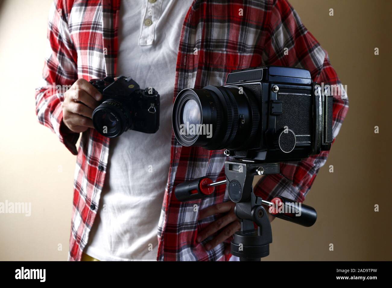 Photo of a man holding a 35mm film camera and standing behind a medium ...