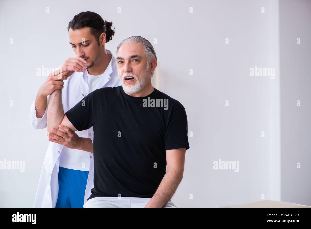 Old injured man visiting young doctor Stock Photo - Alamy