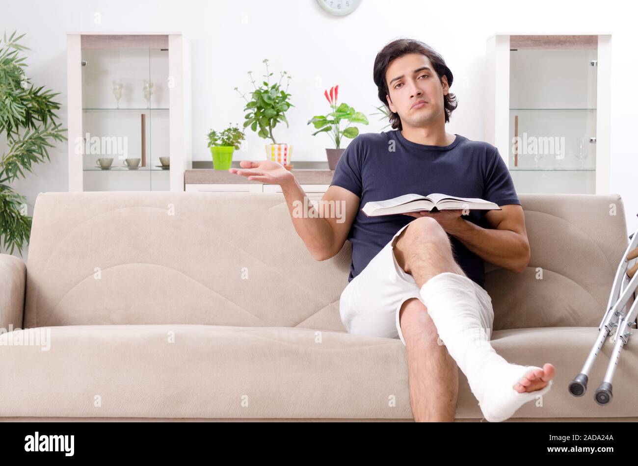 Leg injured young man suffering at home Stock Photo - Alamy