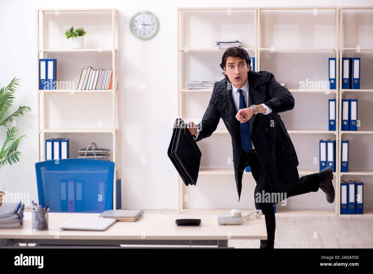 Young male employee in the office in time management concept Stock ...