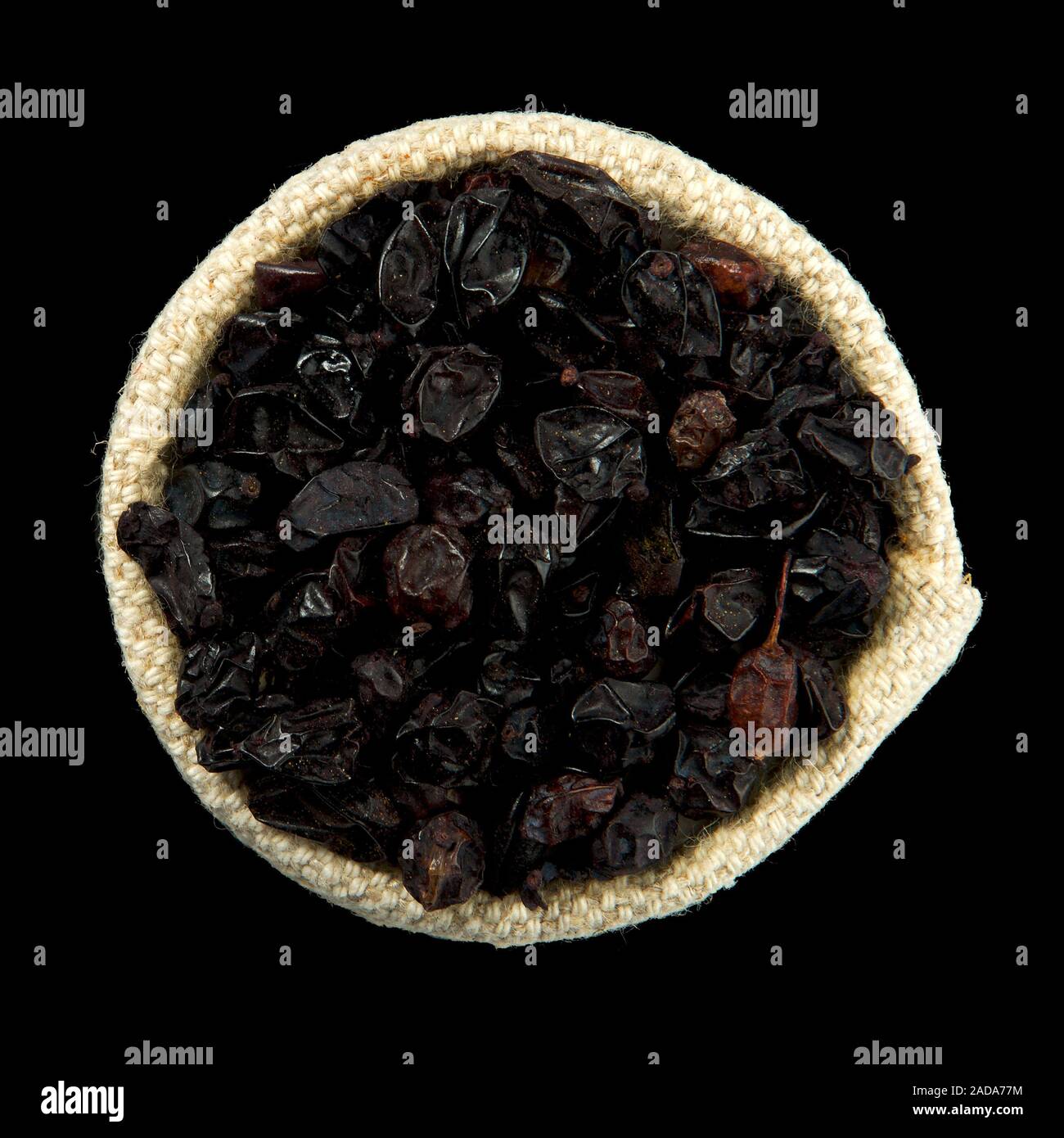 Dried barberry in a bag isolated on a black background. Seasoning on ...
