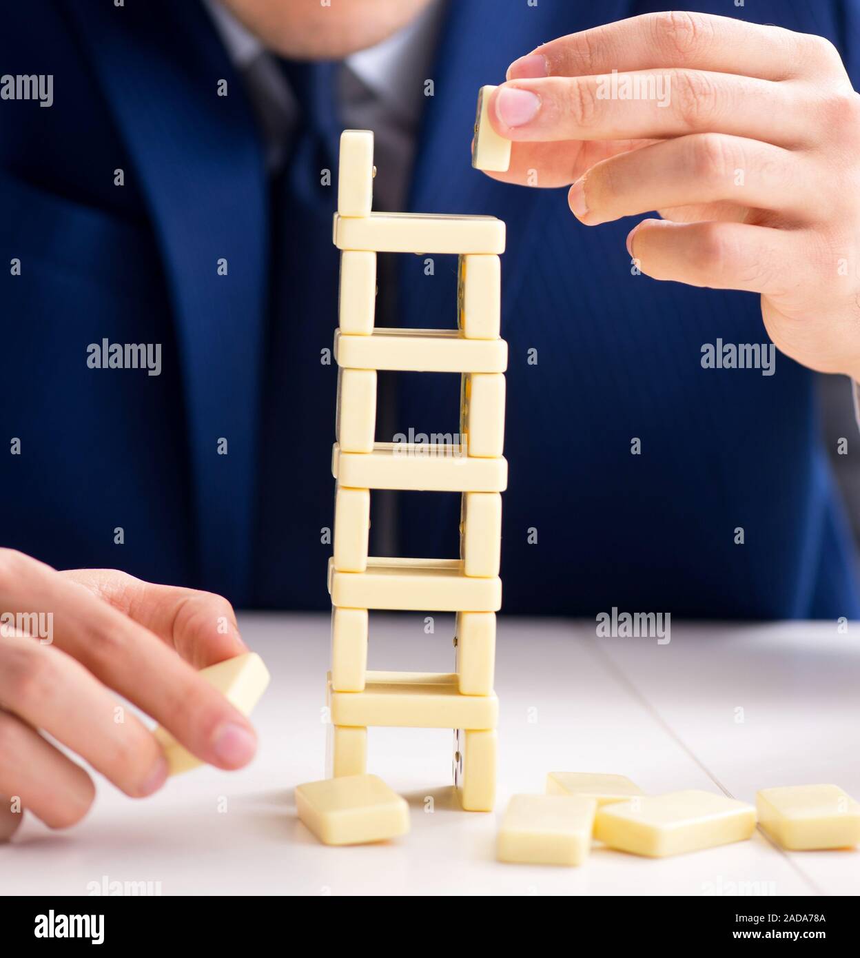 Young Businessman building domino tower in office Stock Photo - Alamy