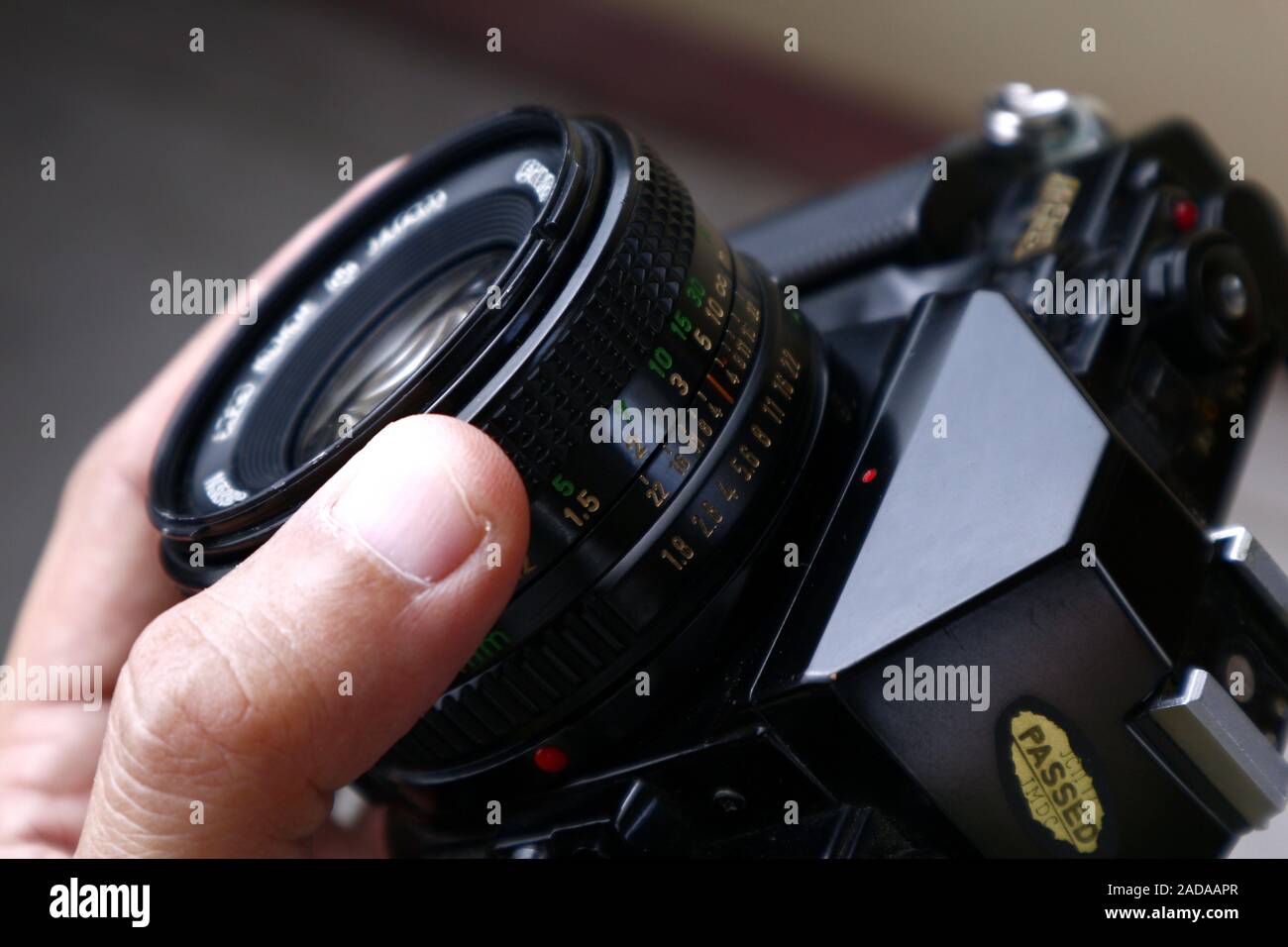 Photo of a hand holding the focusing ring on the lens of an old and ...
