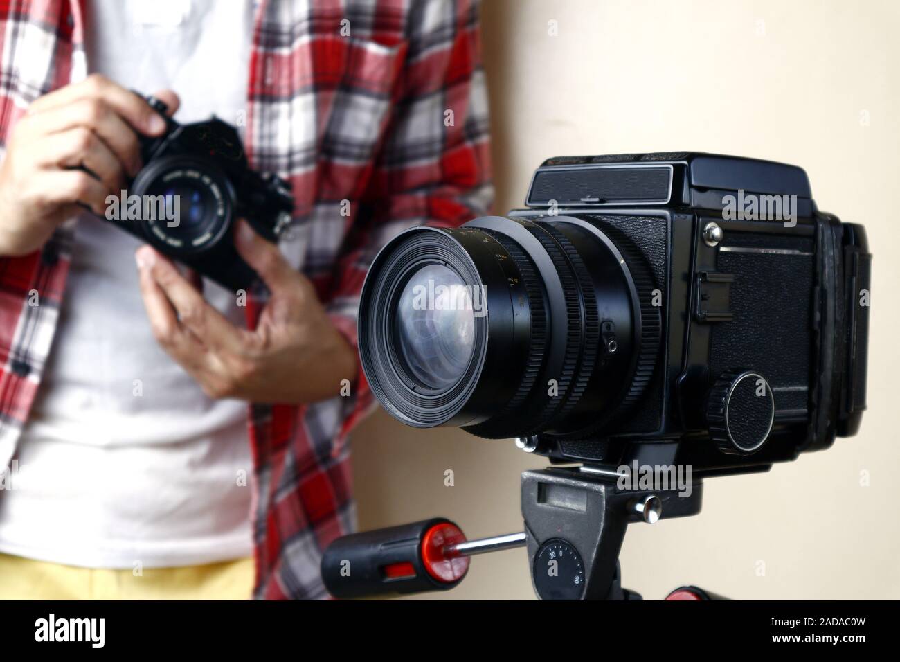 Photo of a man holding a 35mm film camera and standing behind a medium ...