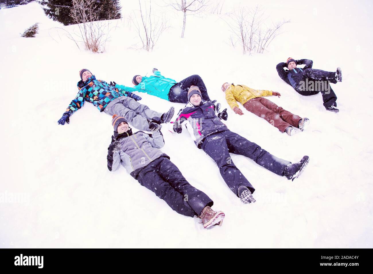 group of young people laying on snow and making snow angel Stock Photo ...