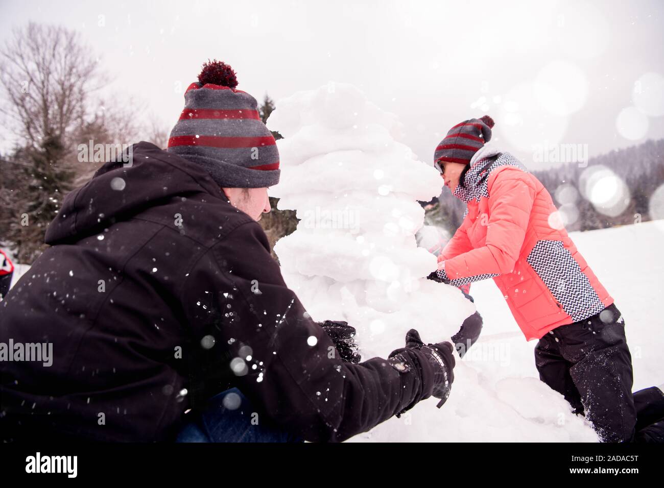 group of young people making a snowman Stock Photo - Alamy