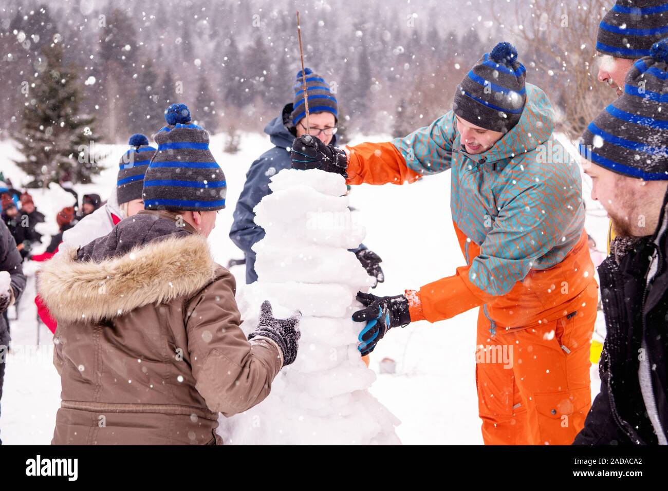 group of young people making a snowman Stock Photo - Alamy